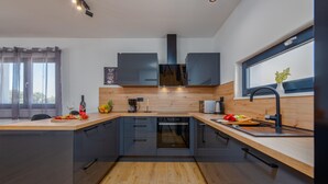 Cozinha moderna com armários escuros, bancada de madeira e forno embutido.