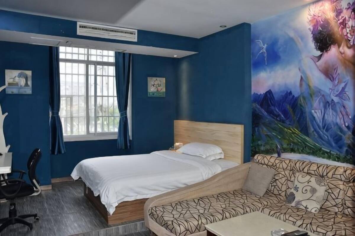 Quarto com cama, sofá, escrivaninha e janela.