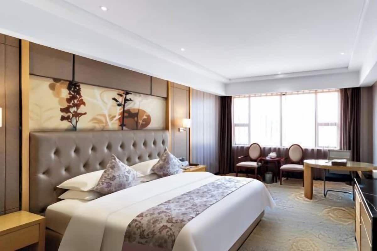 Quarto de hotel com uma cama grande, uma escrivaninha e uma cadeira.