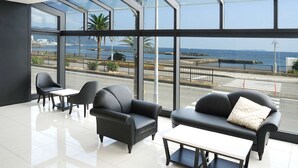 Interior moderno com vista para o mar, com um sofá, cadeiras e uma mesa.