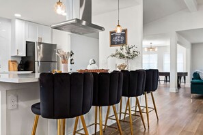 Cozinha moderna com ilha central, eletrodomésticos de aço inoxidável e luminária pendente.