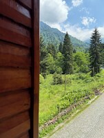 Um caminho de pedras irregulares serpenteia por uma paisagem verde exuberante, com árvores e uma montanha ao fundo.