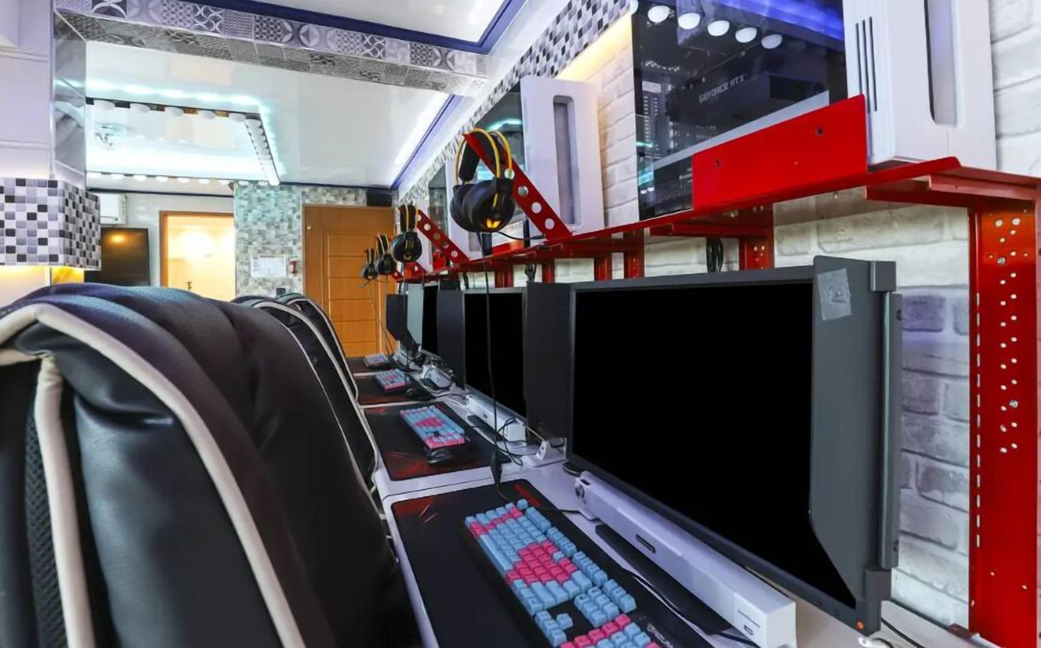 Um espaço gamer com vários monitores, um teclado mecânico e fones de ouvido.