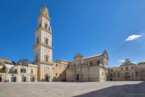 Uma praça histórica com uma igreja imponente, destacando-se por sua torre sineira alta e fachada detalhada.