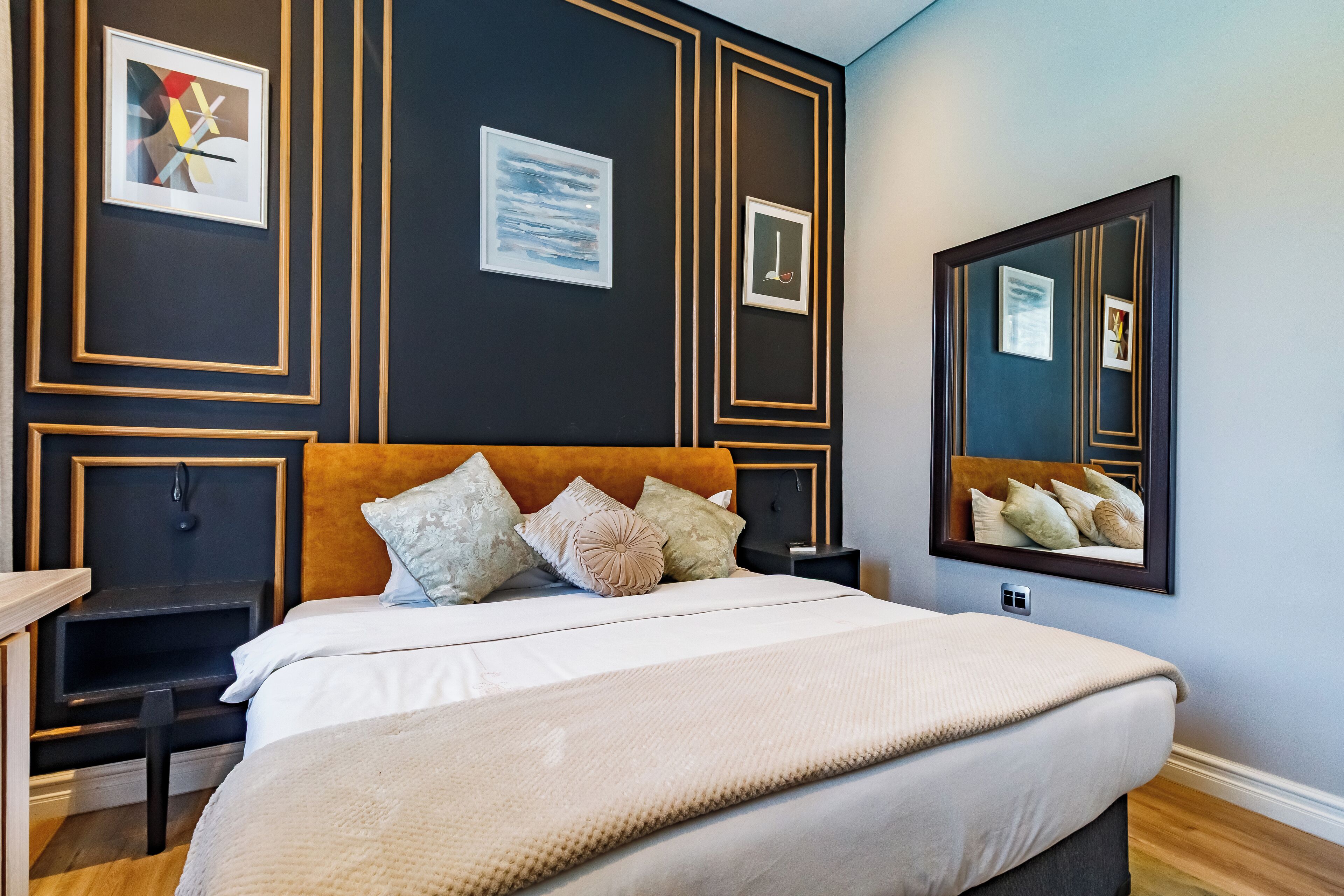 Quarto bem arrumado com uma cama grande, mesas de cabeceira e um espelho na parede.
