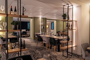 Uma área de jantar moderna com mesas, cadeiras e garrafas de vinho.