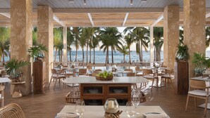 Restaurante à beira-mar com mesas preparadas para refeições, com vista para o oceano.