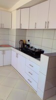 Cozinha com armários brancos, fogão preto e painel de azulejos.