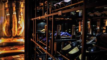 Uma adega com prateleiras de garrafas de vinho e um suporte com taças suspensas.