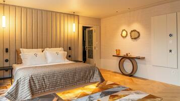 Quarto de hotel moderno com uma cama grande, uma mesa lateral redonda e um tapete com padrão geométrico.
