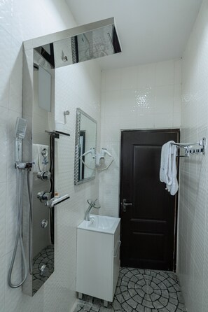 Casa de banho com chuveiro, lavatório e porta.