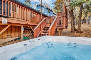 Uma banheira de hidromassagem com um deck de madeira e escadas que levam a uma casa.