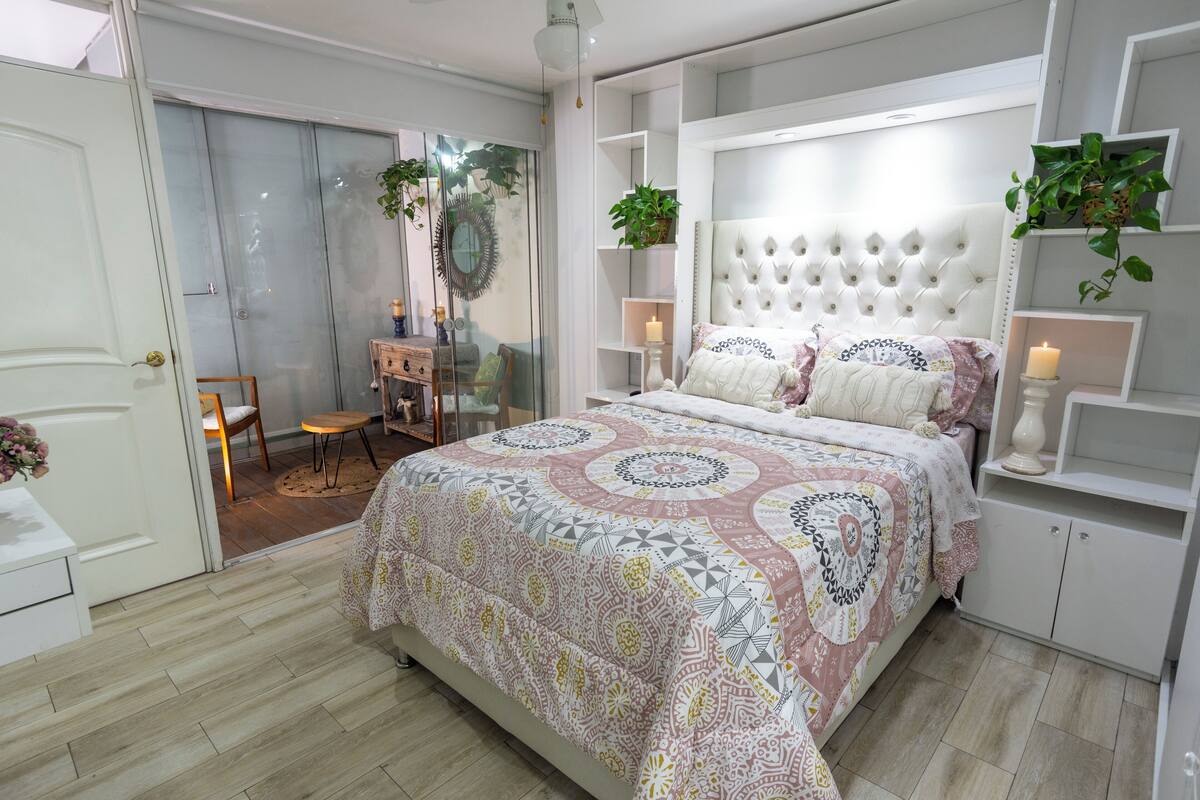 Quarto com uma cama grande, toucador com espelho e um pequeno espaço de estar.