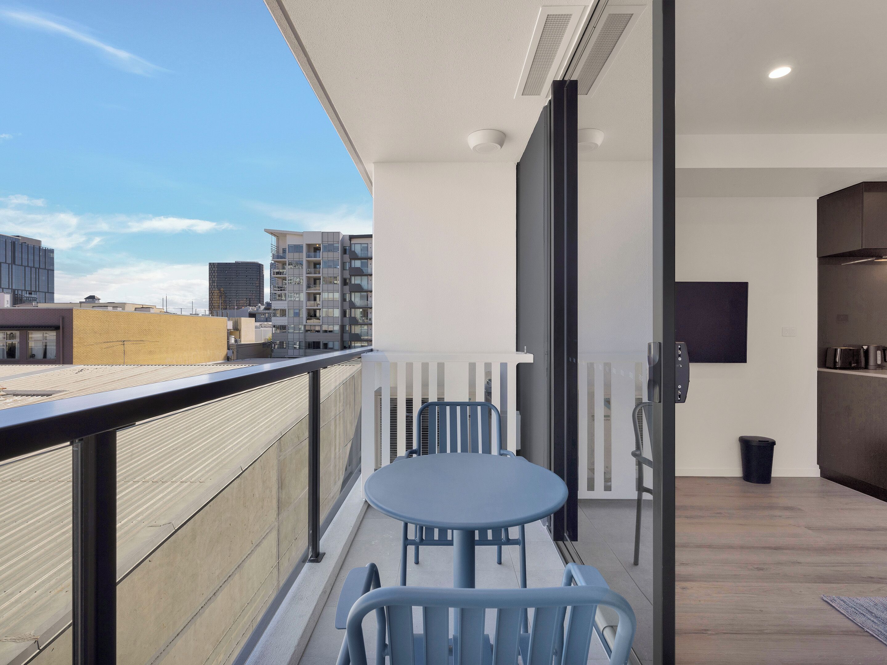 Varanda com mesa e cadeiras, vista para a cidade e cozinha moderna.