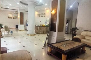 Um saguão de hotel com balcão de recepção, mesa de centro e um sofá.