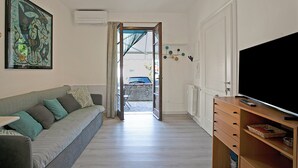Sala de estar com sofá, televisão e porta que dá para o exterior.