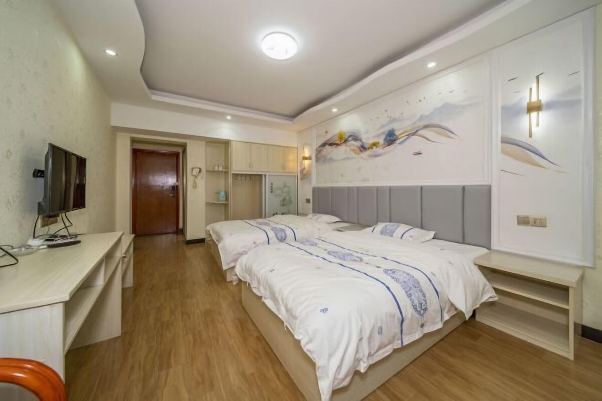 Quarto de hotel com uma cama grande, escrivaninha, televisão e guarda-roupa.