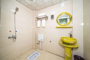 Casa de banho com chuveiro, sanita, lavatório e espelho.