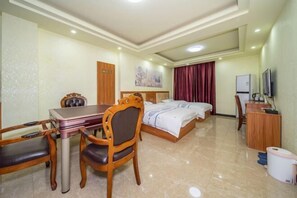 Quarto de hotel com uma cama, uma escrivaninha, uma cadeira, uma televisão e um pequeno armário.