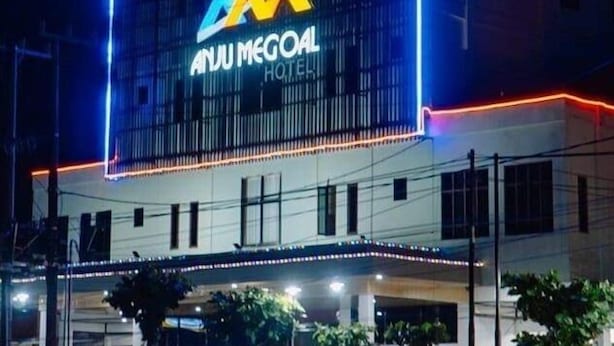 Um hotel com uma placa grande com a inscrição "AMU MEGOAL HOTEL" e um design arquitetônico moderno com bordas iluminadas.