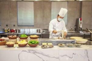 Cozinheiro em cozinha profissional, com diversos pratos e utensílios de cozinha.