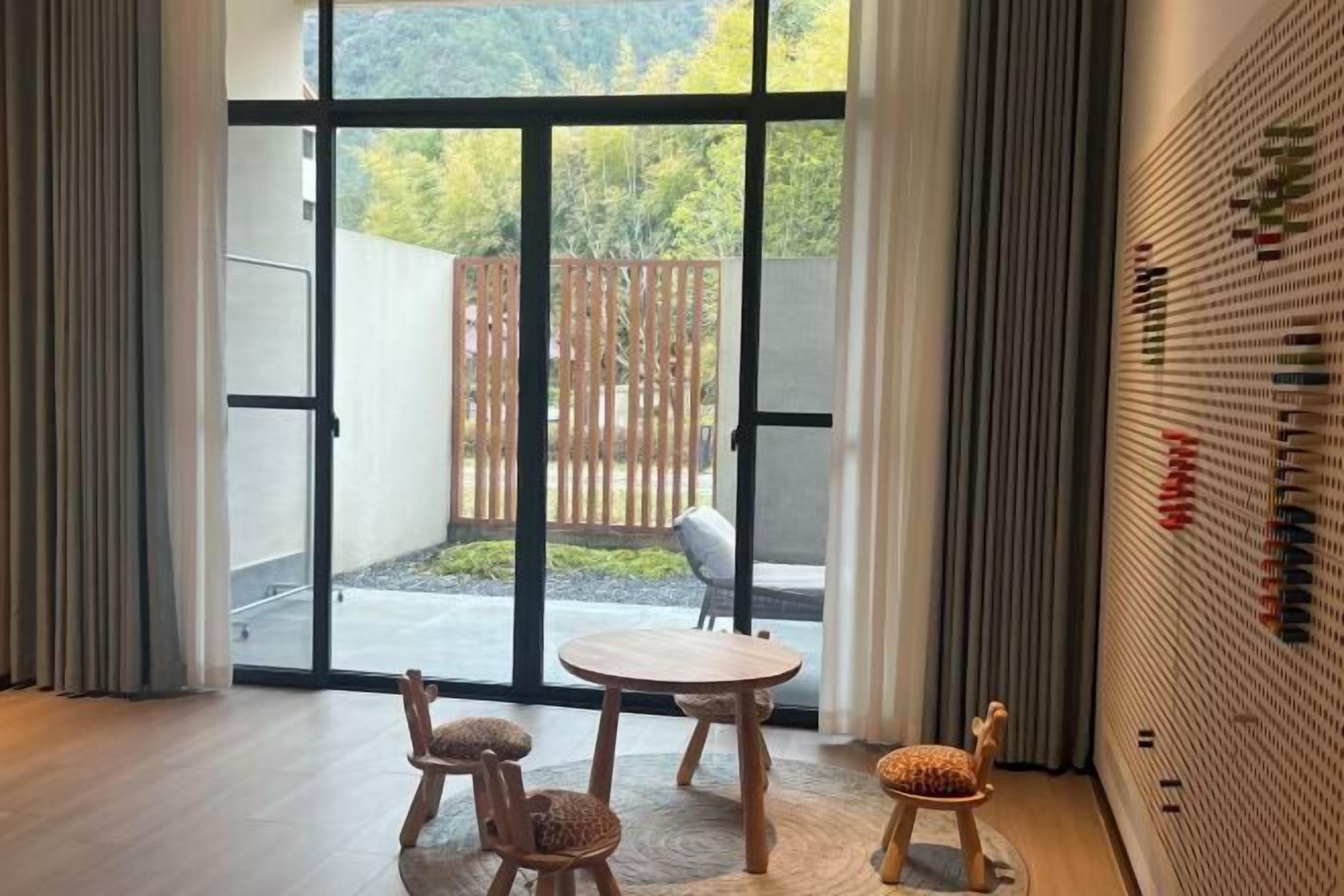 Quarto com porta de vidro deslizante para um pátio, uma mesa de madeira redonda e duas cadeiras.