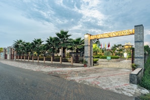 Uma entrada com portão para um hotel, com a placa 'GALAXY GARDEN RESORT'.