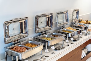 Uma mesa de buffet com diversos alimentos e utensílios.
