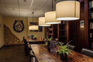Uma sala de conferências com mesa de madeira, cadeiras de couro e luminárias pendentes.
