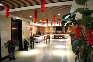 Um saguão de hotel com balcão de recepção, área de atendimento e espaço para sentar.