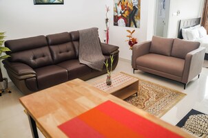 Uma sala de estar moderna com um sofá de couro marrom, uma mesa de centro de madeira e um tapete estampado.