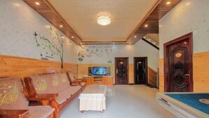 Uma sala de estar espaçosa com um conjunto de sofá de madeira, uma televisão e uma pequena mesa.