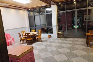 Um quarto com chão quadriculado, uma mesa redonda com cadeiras e um balcão de madeira.