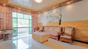 Um quarto espaçoso com teto de madeira, uma janela grande, um conjunto de sofás e uma mesa de massagem.