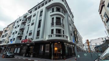 Hotel com fachada curva, várias varandas e entrada destacada.