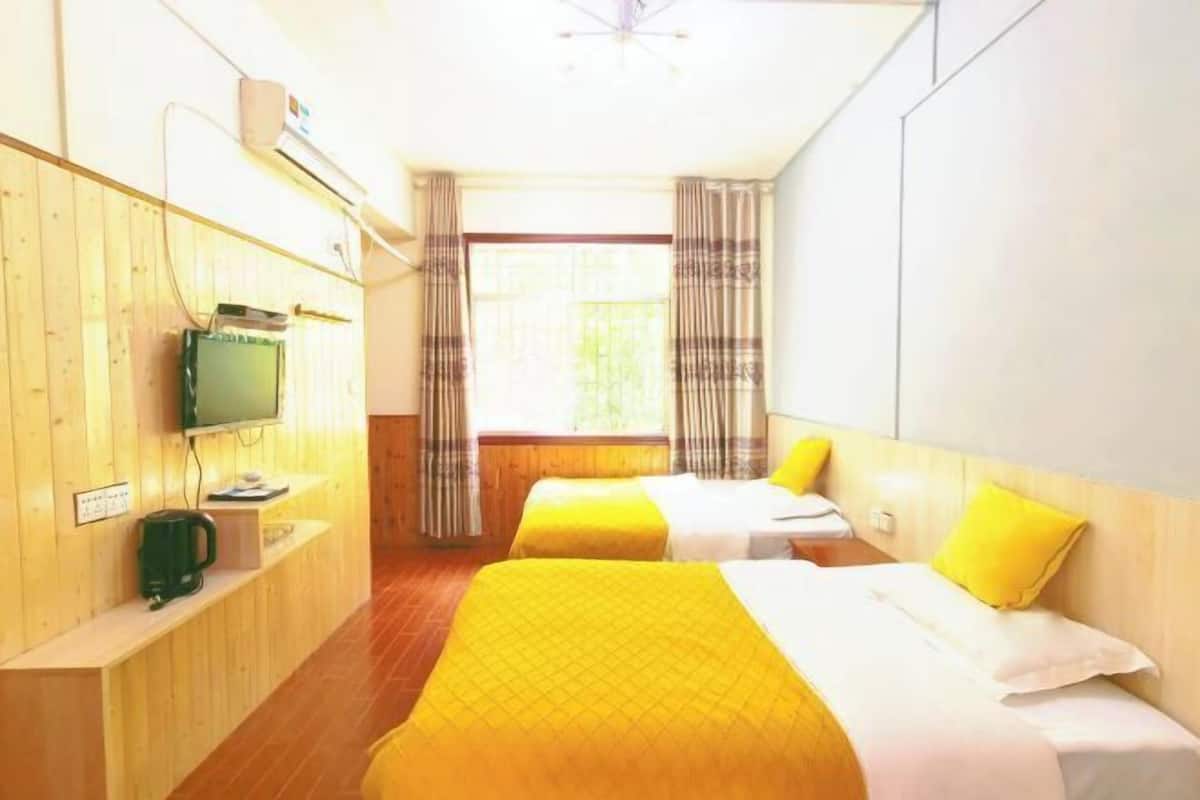 Quarto de hotel com duas camas, televisão, cafeteira e janela com cortinas.