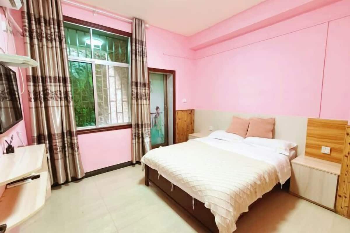Um quarto com cama, mesa de cabeceira e escrivaninha.