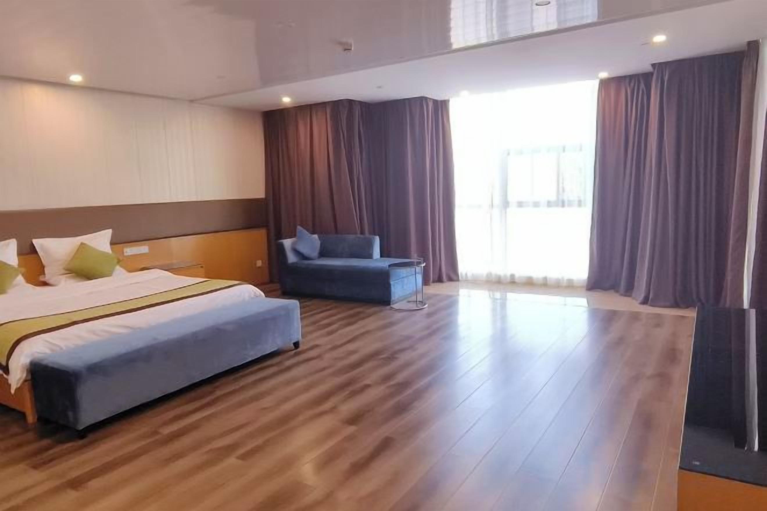 Quarto de hotel com uma cama grande, área de estar e vista pela janela.