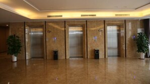 Um lobby moderno com três elevadores, cada um identificado com o número 6F.