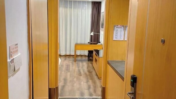 Um corredor de hotel com portas de madeira, uma escrivaninha e uma cadeira.