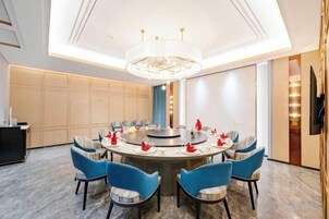 Mesa de jantar redonda com cadeiras azuis, um candelabro e design de interiores moderno.