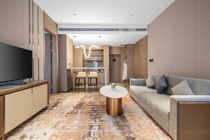 Uma sala de estar moderna com televisão de tela plana, uma mesa de centro redonda, um sofá e um espaço de refeições com cadeiras.