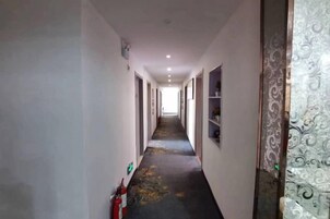 Um corredor com piso coberto por carpete, paredes brancas e papel de parede estampado à direita.