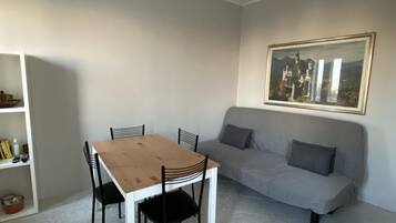 Uma sala de estar moderna com uma mesa de jantar, cadeiras, sofá e estante de livros.