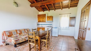 Uma cozinha acolhedora com armários de madeira, painel de azulejos e um espaço de refeições com mesa e cadeiras.