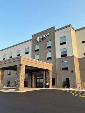Hotel Riverstone Suites com design moderno, apresentando uma entrada coberta e pilares de pedra.