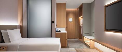 Quarto de hotel com duas camas, uma escrivaninha, um espelho e uma televisão.