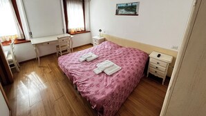 Quarto com cama, escrivaninha e cadeira.