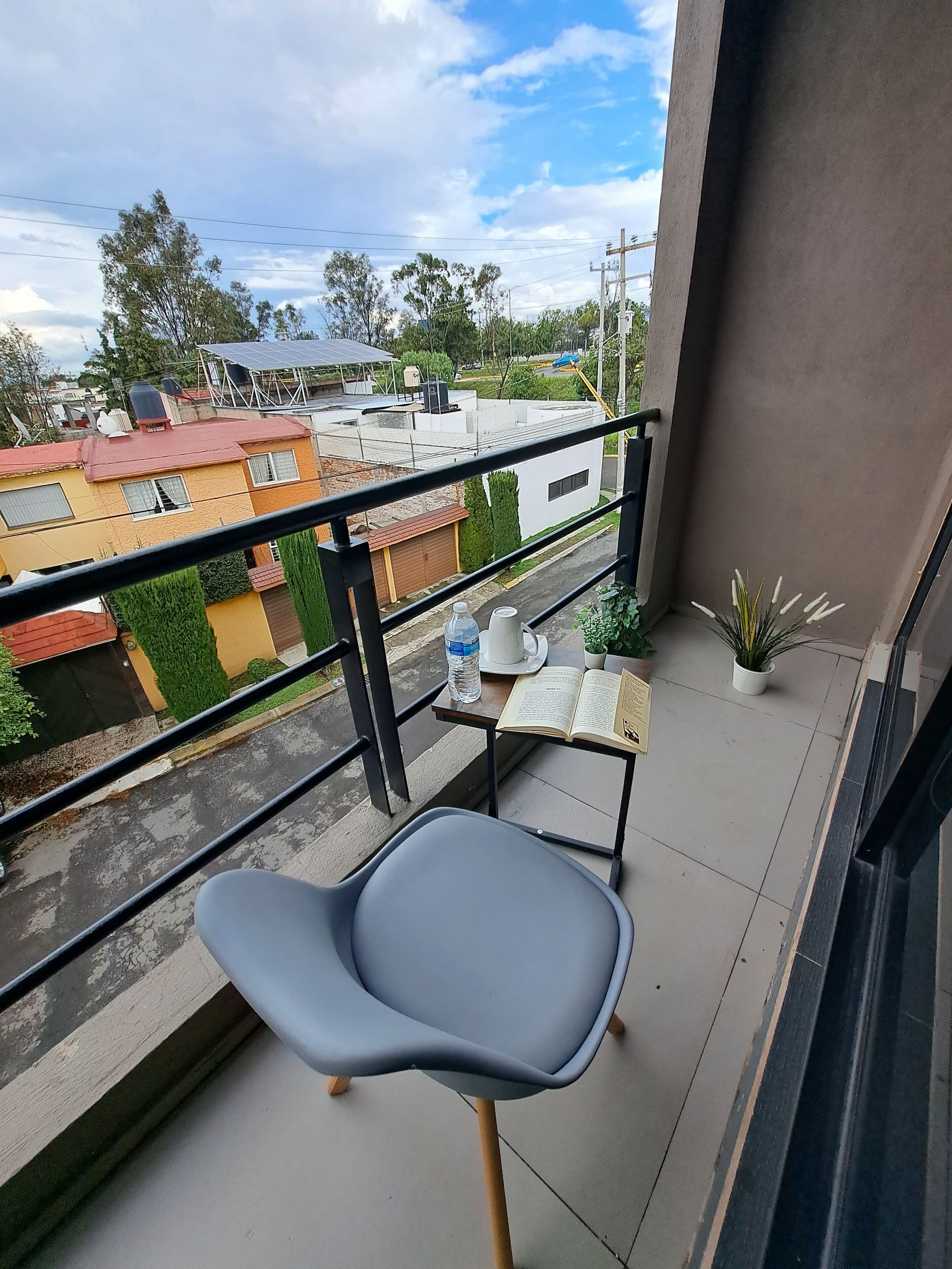 Uma varanda com uma cadeira, uma mesa e um vaso de planta.