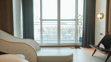 Quarto moderno com uma janela grande, um sofá, uma cadeira e um par de chinelos no chão.